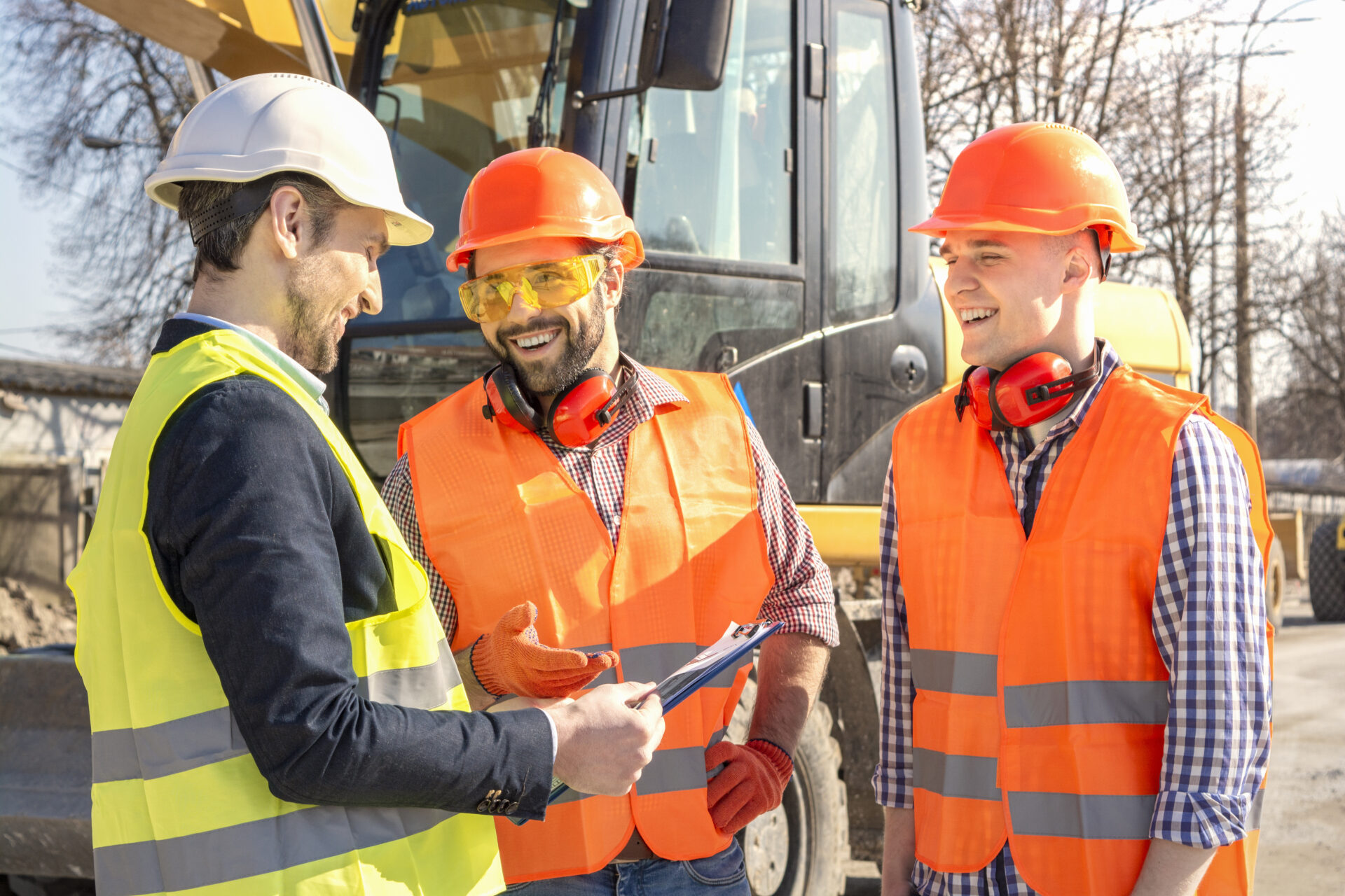 male workers engineers in helmets talking near the bulldozer and ...